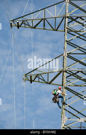 Worker climbing electricity pylon Stock Photo - Alamy