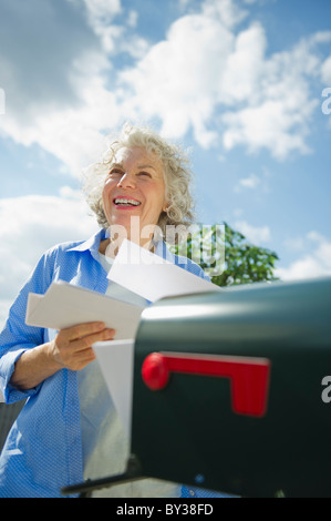 Woman reading mail while standing by mailbox Stock Photo - Alamy