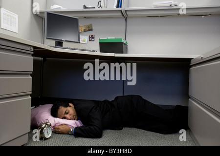 A man sleeping underneath his desk in his cubicle at work Stock Photo ...