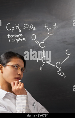 Female student thinking hard about chemistry problem on blackboard ...