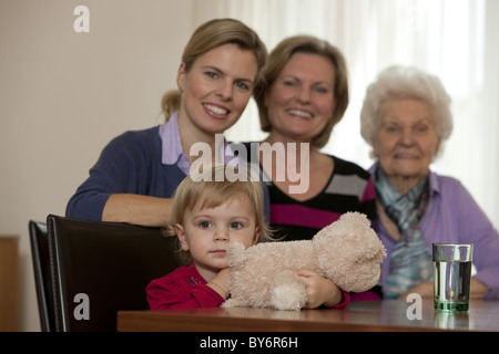 Four generations of one family sitting at a wooden table in the garden ...