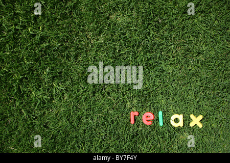 The word 'relax' spelled out in colourful plastic letters, on green ...