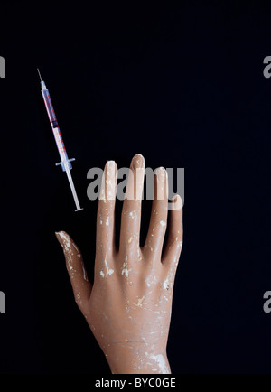 Drug addiction. Mannequin hand with syringe and pills on black wooden ...