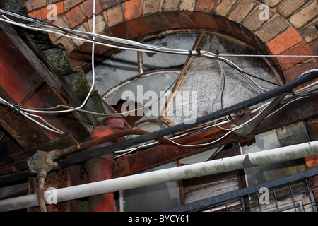 A wiring disaster on the outside of a building next to the downpipe and ...