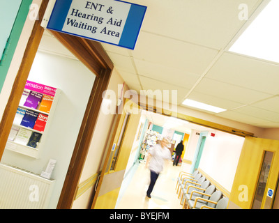 Waiting area signage in a NHS uk hospital as a doctor walks through the ...
