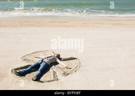 Girl making angel in sand on beach, high angle view Stock Photo - Alamy