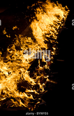 Flames rising from a firewalk in preparation using lines of wood logs ...