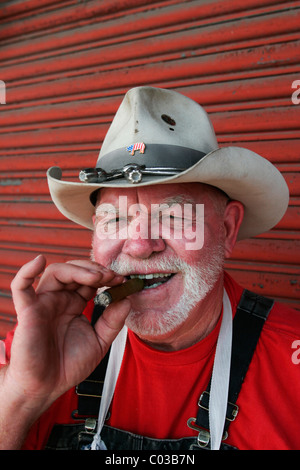 Older man smoking cigar outside in home backyard garden. Happy senior man enjoying retirement ...
