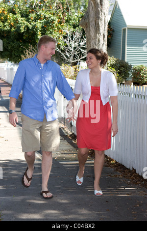A couple hold hands while walking along an old farm road Stock Photo ...