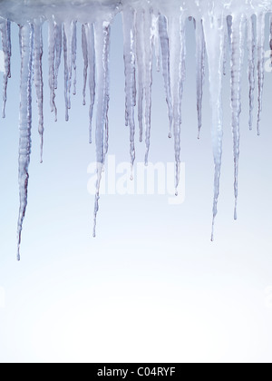 Large icicles hanging on the roof of the wooden house in winter time ...