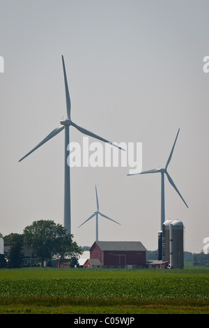 Windmill turbines with a green field with crops and a blue sky green ...