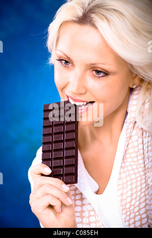 A young woman bites into a bar of chocolate Stock Photo - Alamy
