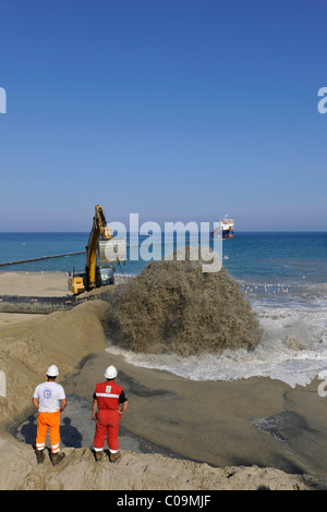 Dredger pumping sand through a hose onto a beach for beach nourishment ...