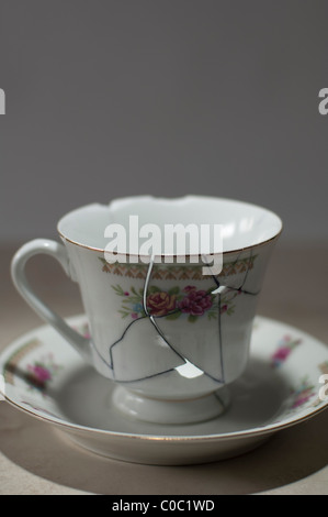 Clumsily repaired leaky teacup with cracks Stock Photo - Alamy