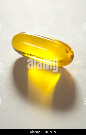Macro Close up of Omega 3 gel capsule on a reflective black background ...