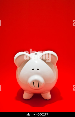 White piggy bank on red background Stock Photo - Alamy