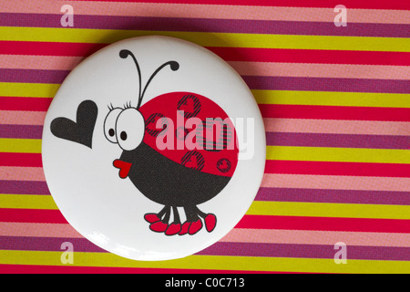ladybird round pin badge on striped background Stock Photo - Alamy