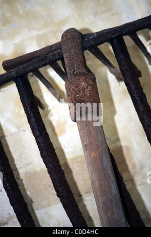 Old rusted rake hanging on the exterior of traditional log wall painted ...