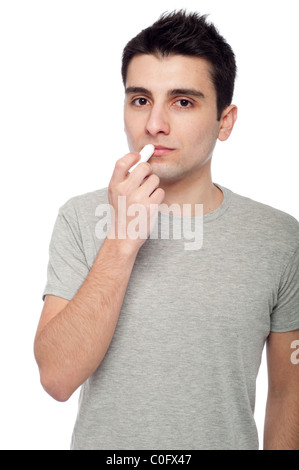 Handsome man applying lip balm onto his lips on grey background Stock ...