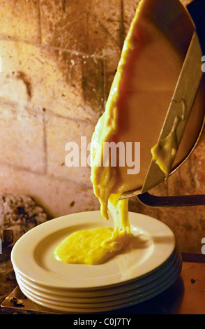 Wheel of raclette cheese melting before fireplace Stock Photo - Alamy