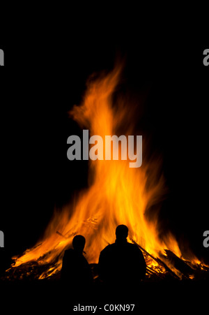 Two people watching the fire burn Stock Photo - Alamy