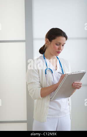 Portrait of a female nurse writing down patient information standing ...