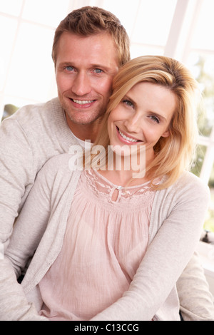 Smiling couple in love on a swing outdoors looking to each other ...