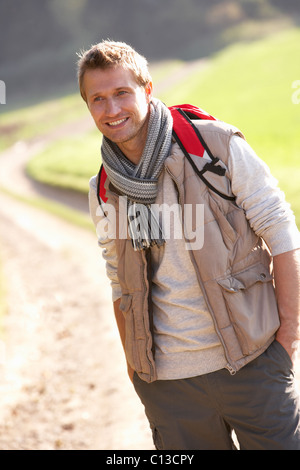 A young man poses outdoors in a patterned vest and lace blouse with ...
