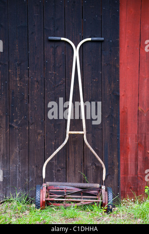 Old-fashioned push lawn mower leaning against a wooden wall Stock Photo ...