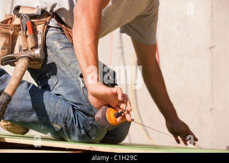 A carpenter marking a section of wood using a combination square Stock ...