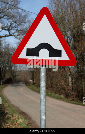 Hump back bridge road traffic sign partly hidden by foliage, Shingle ...