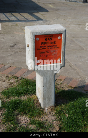 Gas pipeline marker post, warning of gas pipes below ground, on grass ...