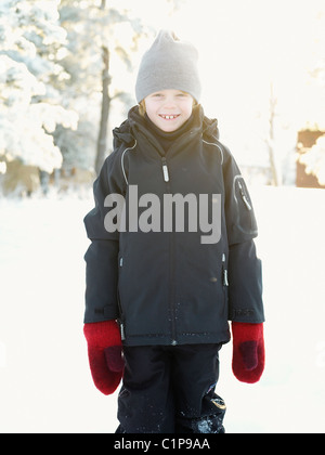 A happy boy in a winter hat and snow-covered mittens. A child in winter with ice sleds Stock ...