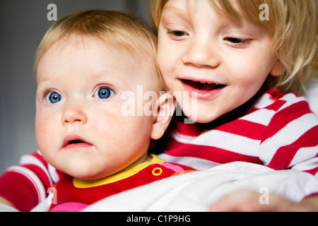 Close-up of happy brother embracing cute sister while standing against ...