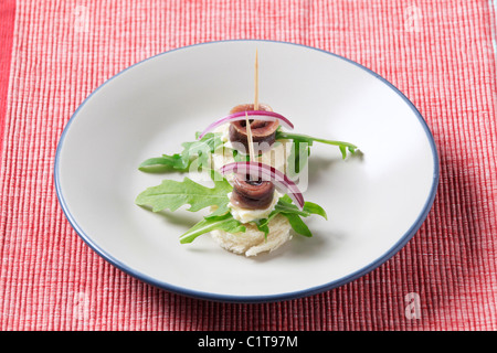 Anchovy canapes garnished with arugula and onion Stock Photo - Alamy