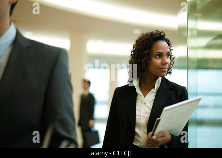Curly haired businesswoman looking through window while contemplating ...