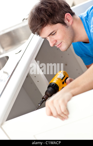 Confident young plumber repairing a sink at the domestic kitchen Stock ...