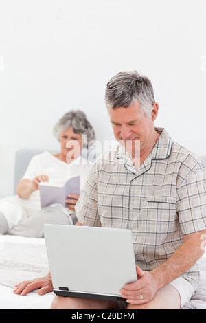 Man working on his laptop while his wife is reading Stock Photo - Alamy