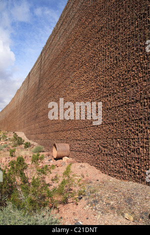 wire mesh and loose rock retaining wall with drain pipe perspective ...