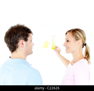 Beautiful couple painting room yellow with paintbrush in theri new ...