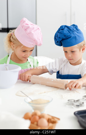 Little chef using rolling pin stretching the dough. Cooking concept ...