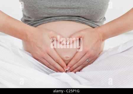 Pregnant woman doing heart sign on her belly Stock Photo - Alamy