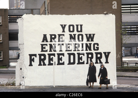 Sign entering Free Derry with mural by Bogside Artists on side of house ...