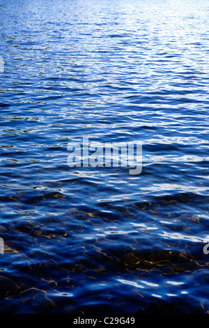 Surface of blue water with slight ripples and blue sky with horizon in ...