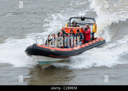 Passengers on a speed boat enjoy a fast ride on the River Thames in ...