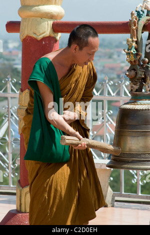 A Buddhist monk is ringing a bell with a piece of wood at a beautiful ...