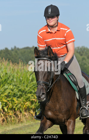 Male in helmet riding by horse at farm, trainer talking to woman in ...