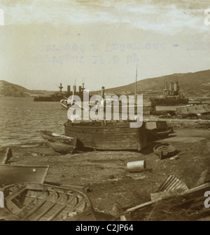 Small boats on shore and warships in harbor; in mid-distance a salvage ...