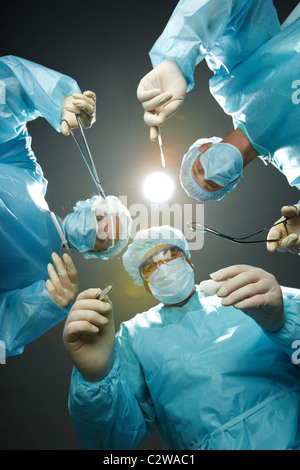 Three surgeons bending over a patient Stock Photo - Alamy