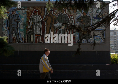 People walk by a Soviet era mural showing people of different ...